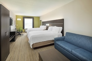 Quarto de hotel com duas camas, um sofá, uma escrivaninha e uma televisão.