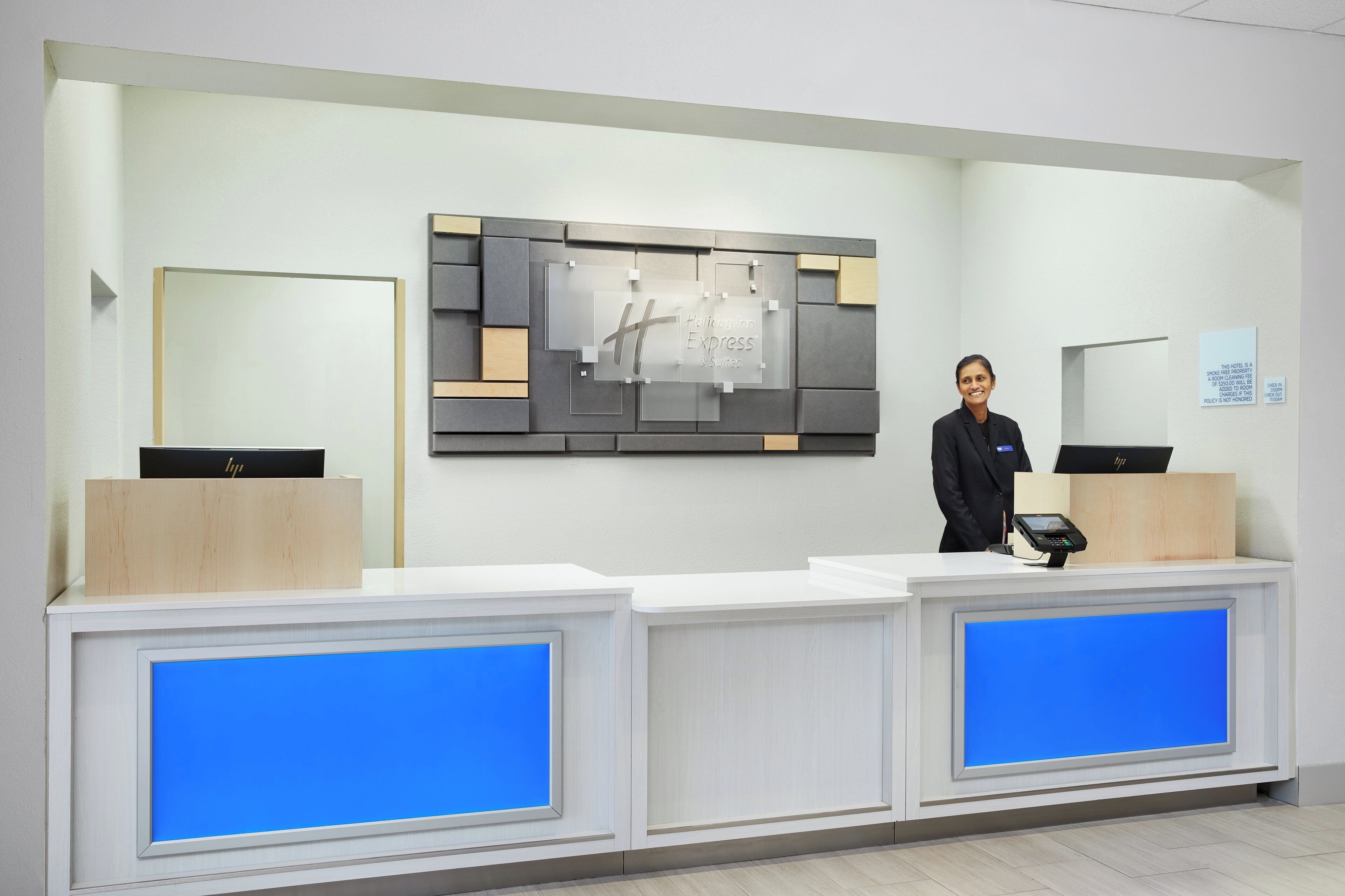 Uma receção de hotel com design moderno, um espelho grande e um posto de check-in digital.