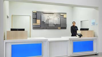 Uma receção de hotel com design moderno, um espelho grande e um posto de check-in digital.