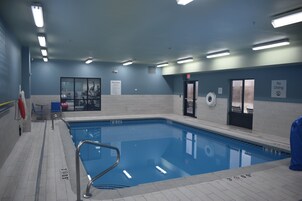 Piscina interior com água cristalina, marcações de profundidade e escada de acesso.