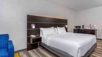 Quarto de hotel com uma cama grande, uma escrivaninha com telefone, micro-ondas e cafeteira.