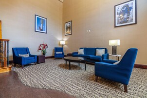Um hall com um sofá azul, uma mesa de centro e um tapete estampado.