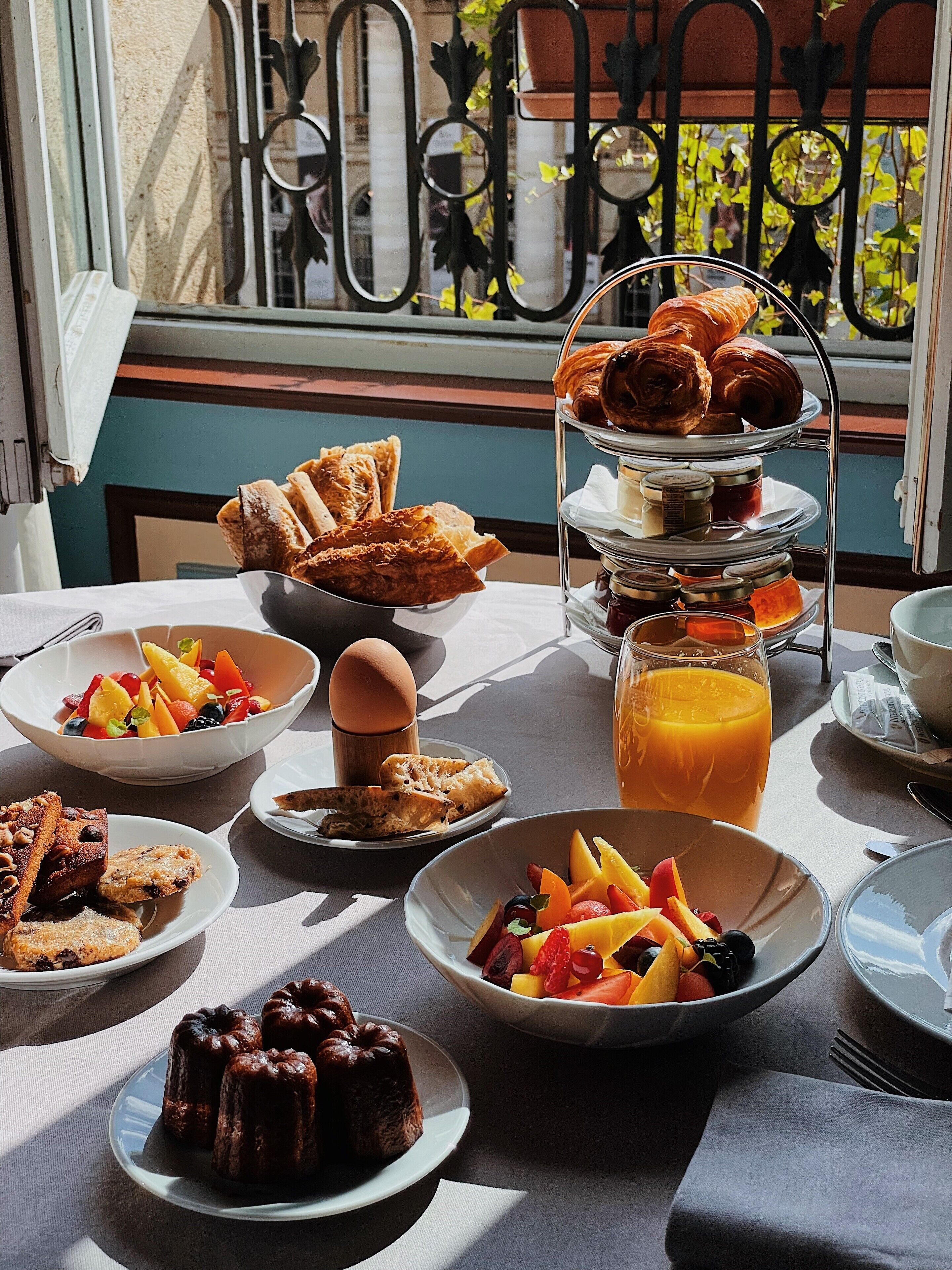 Um buffet de café da manhã com diversos pães, frutas e bebidas.
