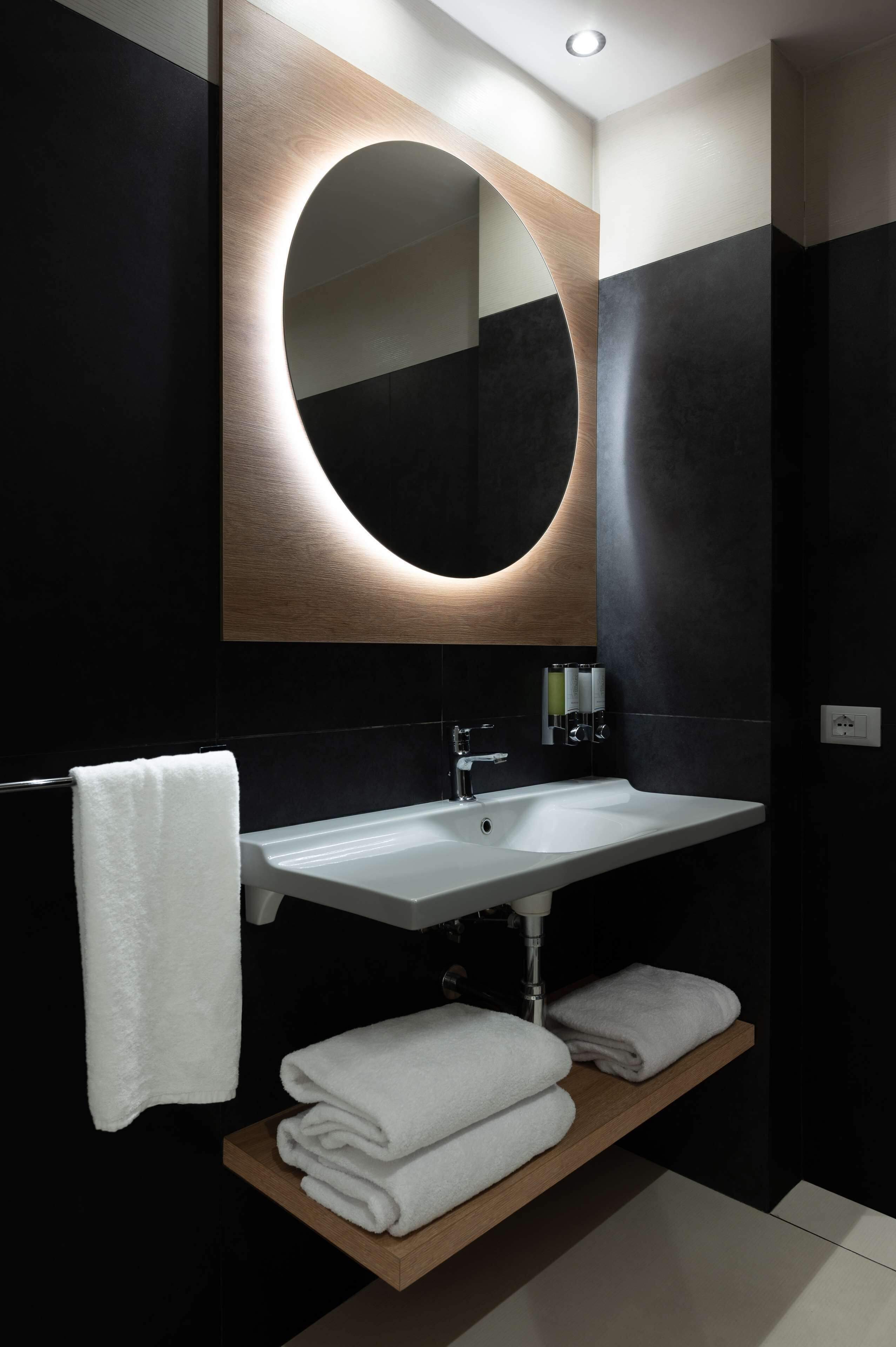 Casa de banho moderna com um espelho grande, lavatório branco e porta-toalhas.