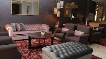 Uma sala de estar com sofá, poltronas, mesa de centro e tapete.