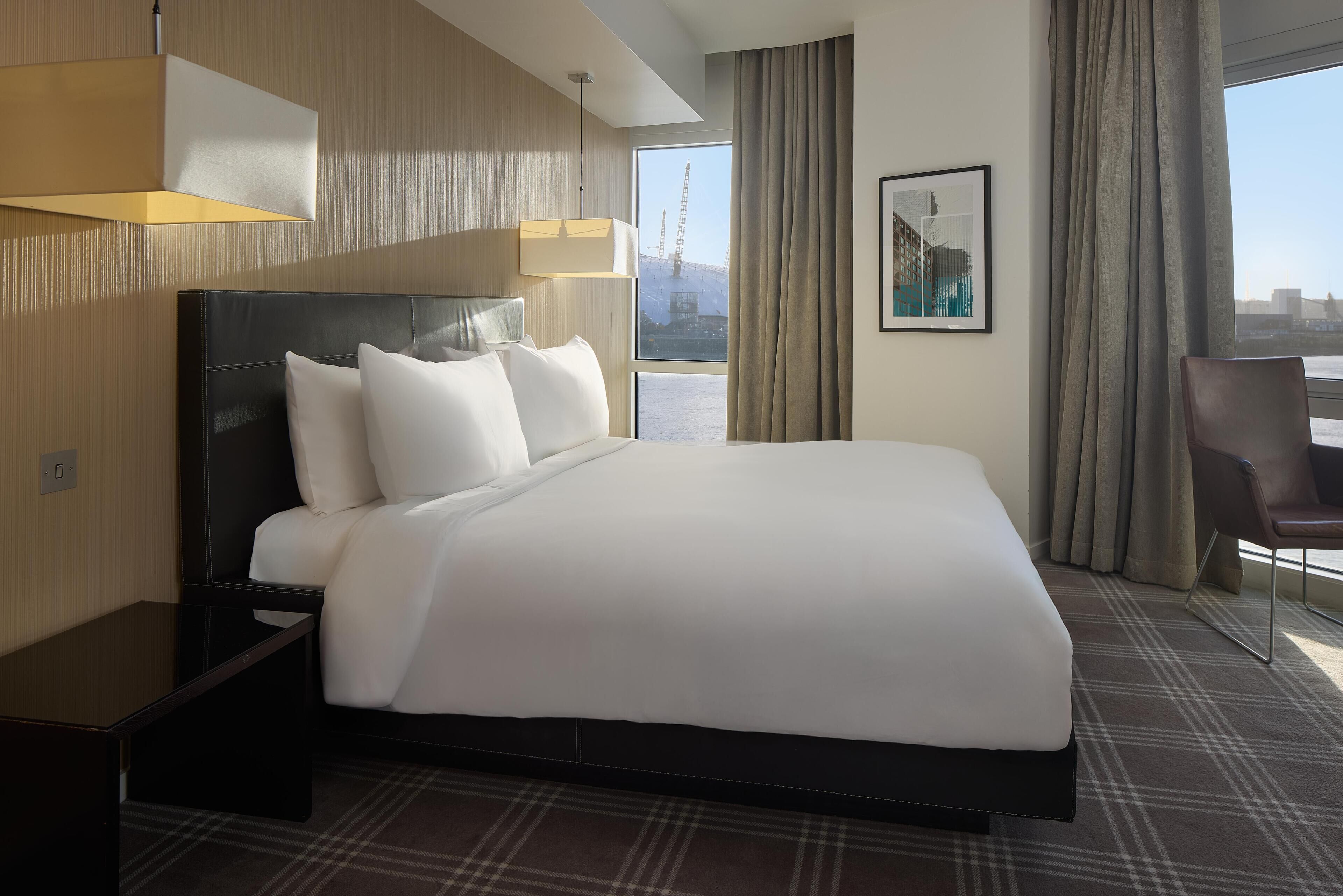 Quarto de hotel moderno com uma cama grande, uma escrivaninha e uma cadeira.