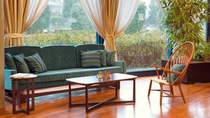 Uma sala de estar com sofá verde, mesa de centro de madeira e uma cadeira de madeira.