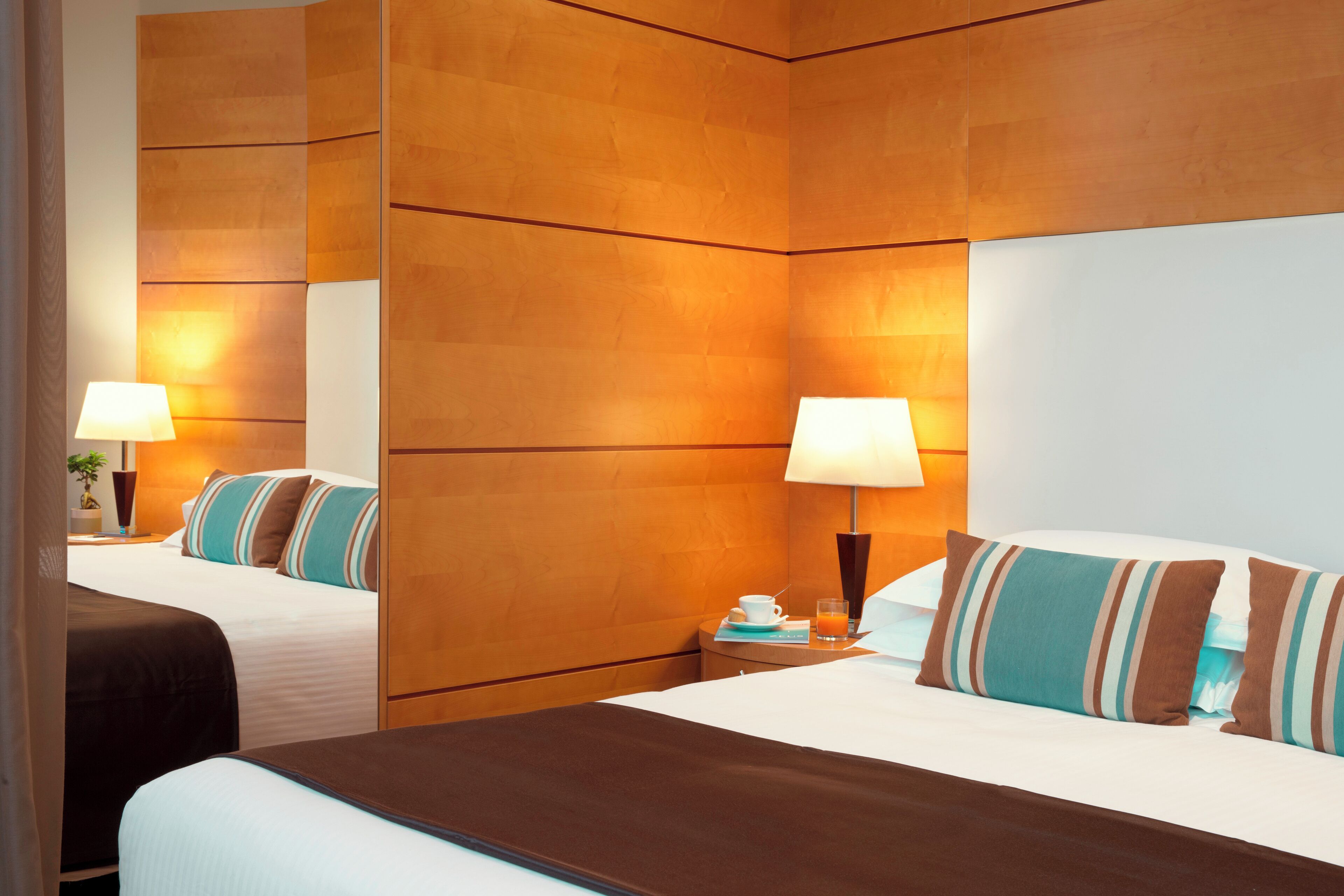 Quarto de hotel com uma cama grande, duas mesas de cabeceira e um espelho.
