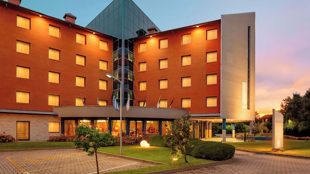 Hotel com design moderno, destacando uma estrutura central de vidro e várias janelas.