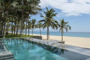 Vista da piscina com praia e palmeiras.