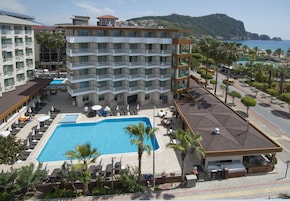 Um hotel com piscina, várias varandas e vista para o mar.
