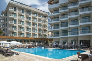 Hotel com piscina, várias varandas e espreguiçadeiras.