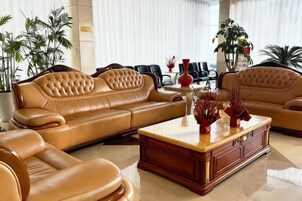 Uma sala de estar ampla com sofás de couro, uma mesa de centro de madeira e plantas em vasos.