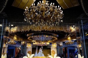 Um lustre ornamentado e um palco com decorações florais.