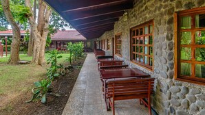Uma área de estar ao ar livre coberta, com paredes de pedra e bancos de madeira.