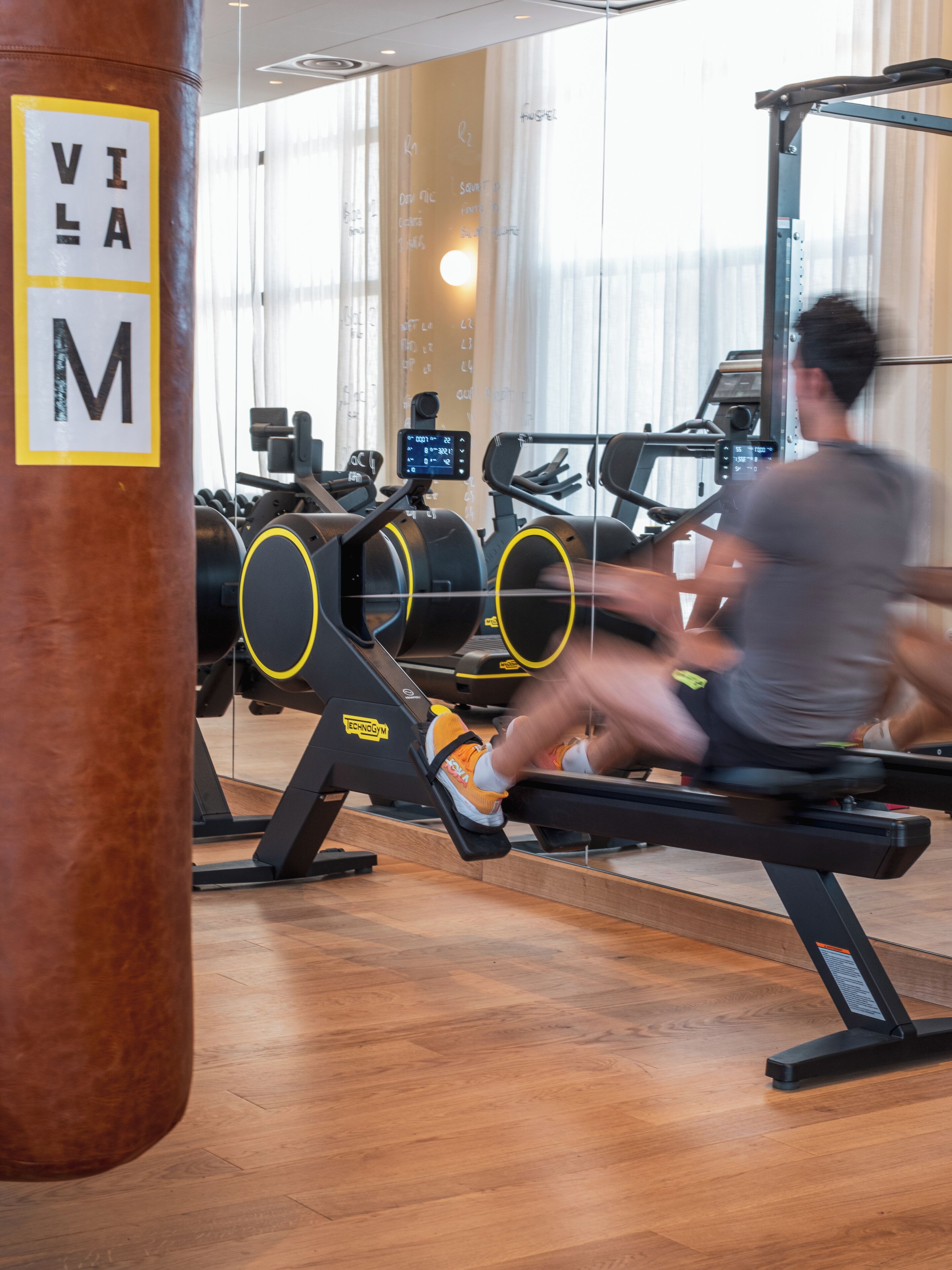Uma academia com equipamentos de ginástica, incluindo uma máquina de remo e esteira.