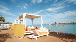 Uma cabana à beira-mar com toldo, duas espreguiçadeiras e uma cadeira de praia amarela.