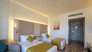 Quarto de hotel com duas camas, um sofá e uma escrivaninha com telefone.