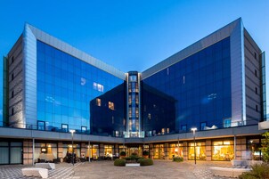 Um hotel moderno com fachada de vidro, um pátio central e áreas de estar ao ar livre.