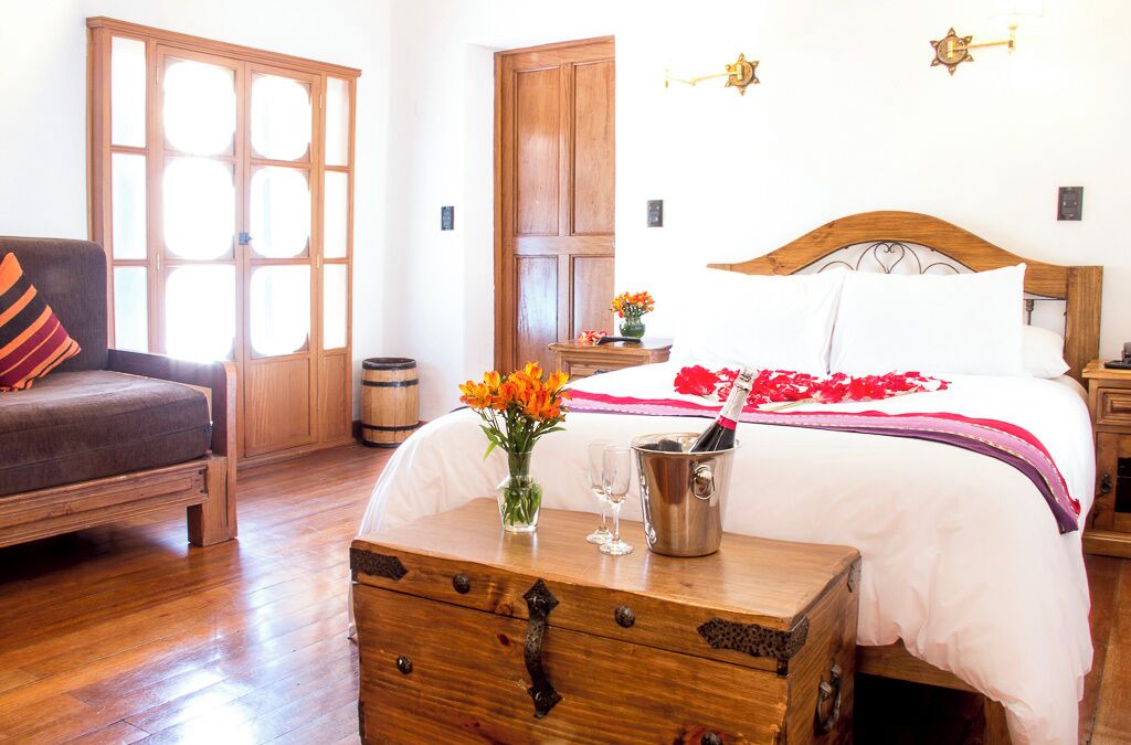 Quarto de hotel com cama, cómoda, sofá e guarda-roupa de madeira.