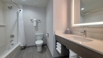 Uma casa de banho moderna com banheira, sanita e toucador com espelho.