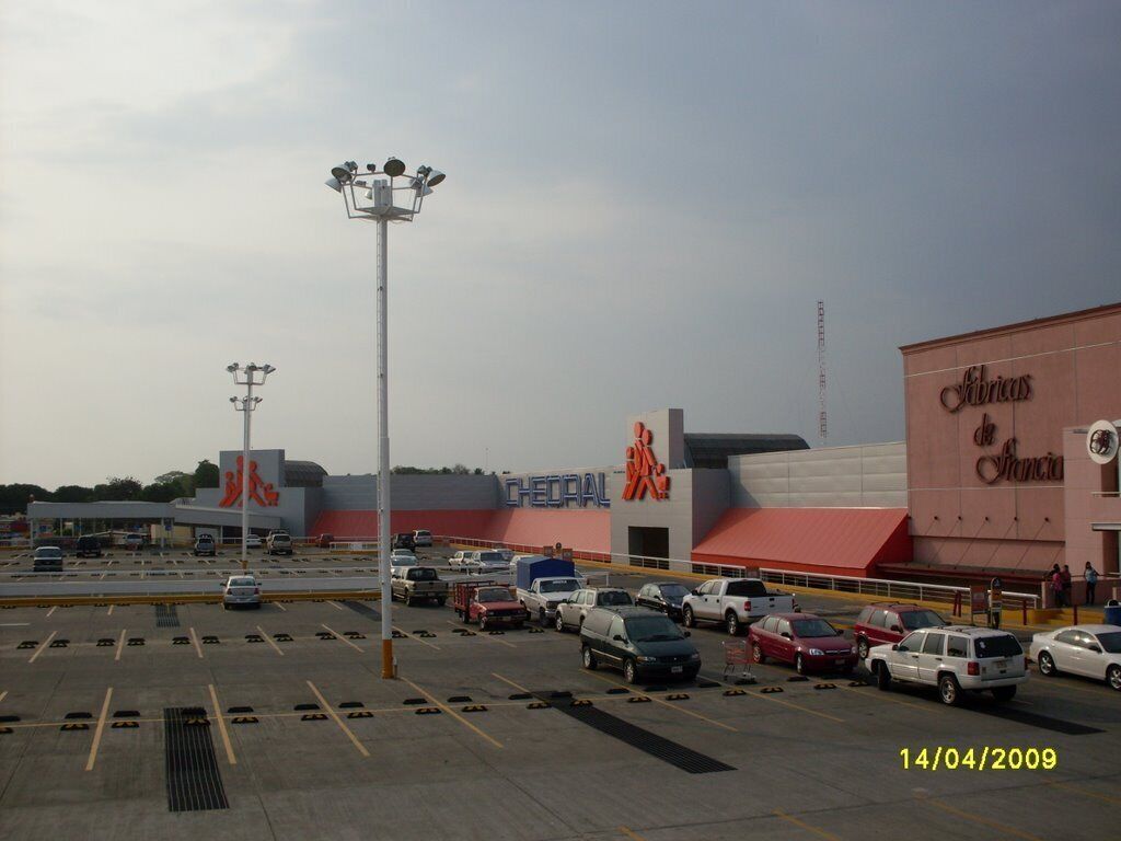 Um estacionamento com vários carros e um edifício grande com placas 'CHEORAL' e 'Africas de Francisco'.