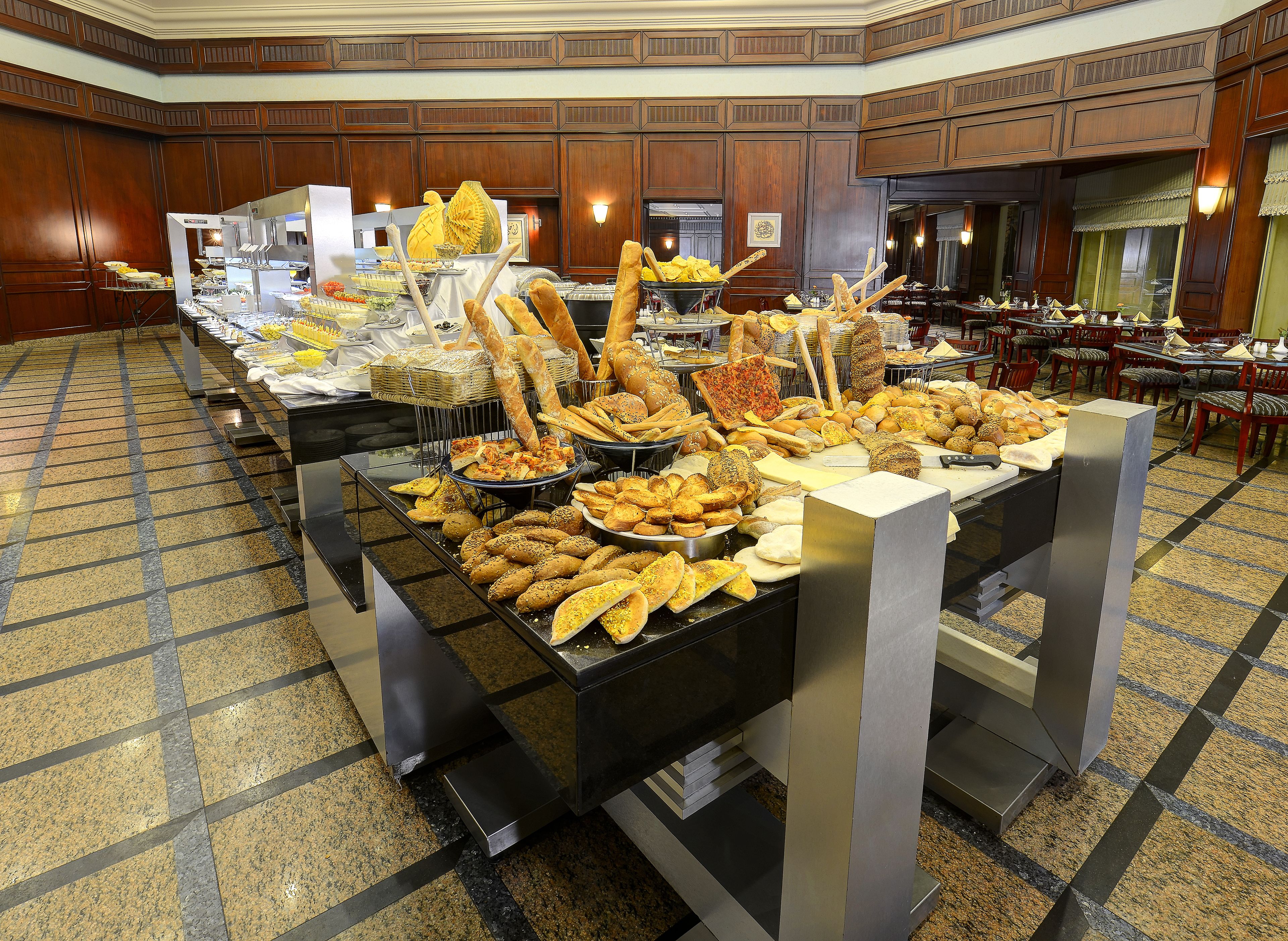 Buffet com diversos alimentos e área de refeições com mesas e cadeiras.