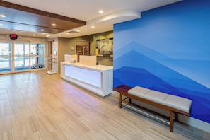 Uma área de recepção com piso de madeira, balcão de atendimento, um banco e parede com design de montanha.