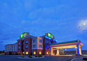 Um hotel Holiday Inn Express & Suites com entrada bem iluminada e estacionamento.