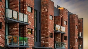 Um edifício moderno de vários andares com fachada de tijolos, janelas grandes e varandas.