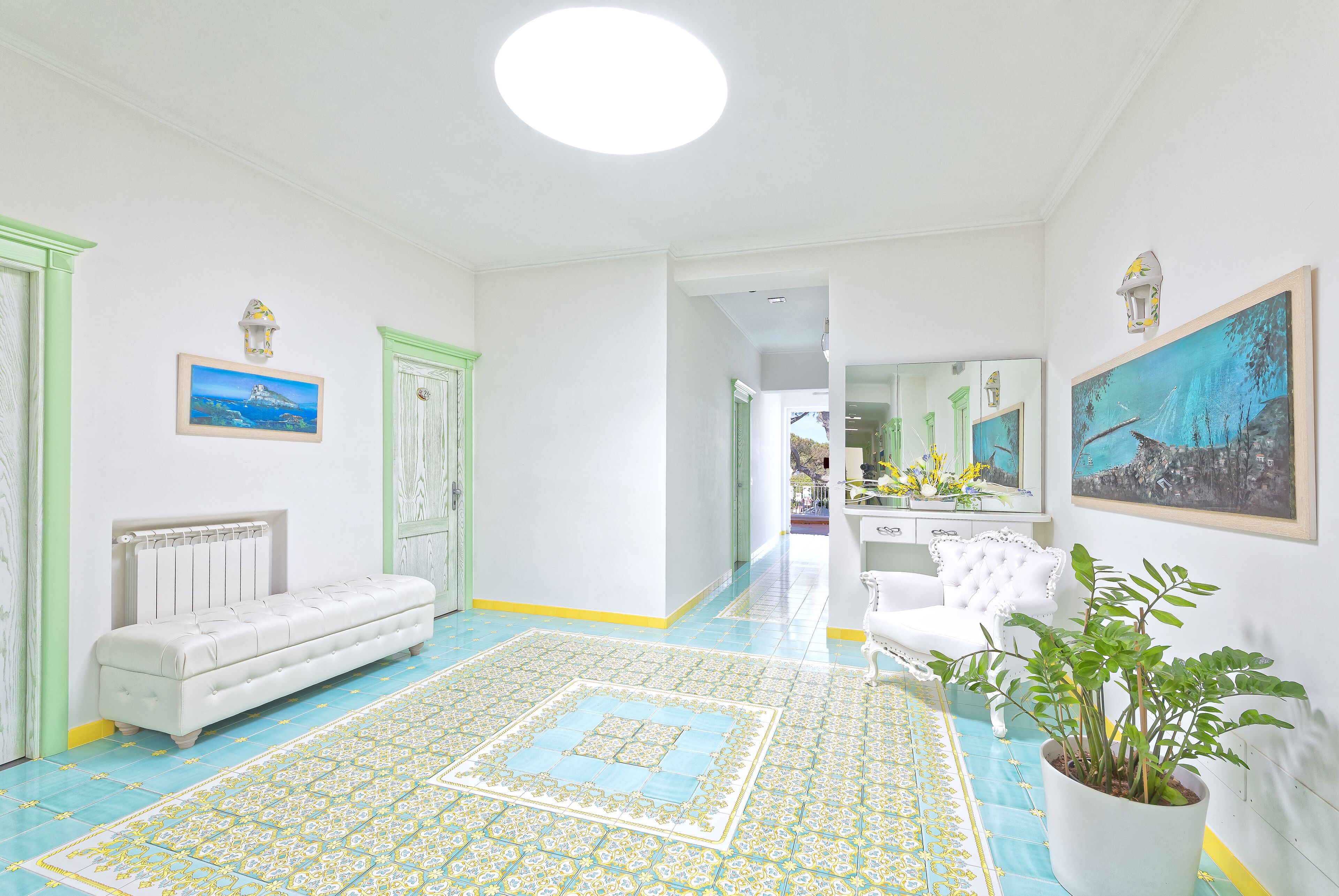 Quarto com um sofá branco, uma planta em vaso e piso estampado.