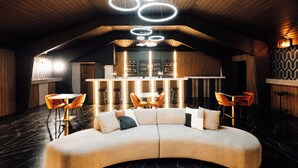 Um interior moderno com sofá curvo, teto de madeira e área de bar com banquetas.
