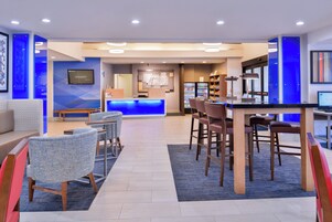 Um saguão de hotel com áreas de estar, balcão de recepção e minibar.