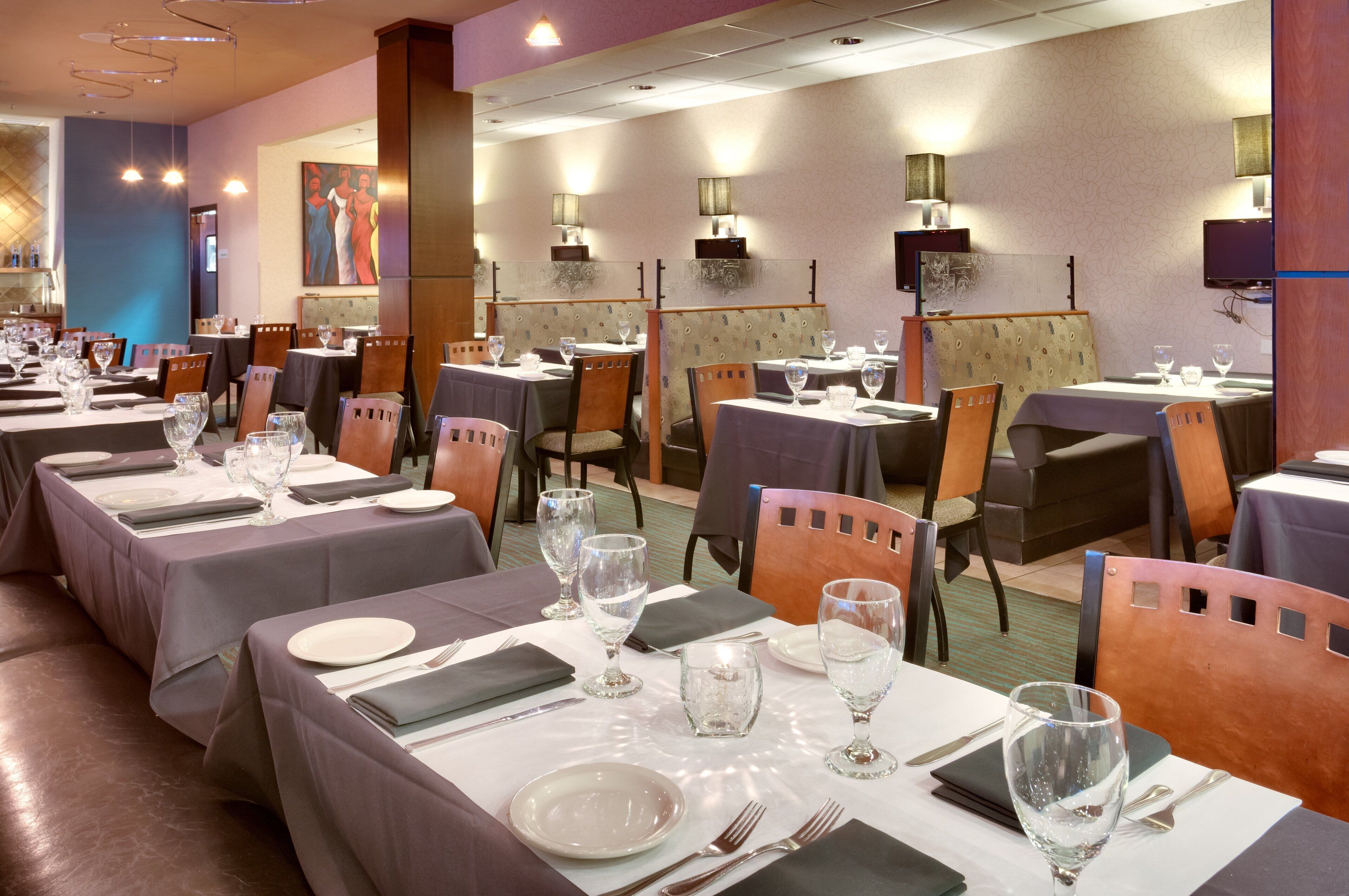 Um restaurante com várias mesas preparadas para refeições, cada uma com pratos, talheres e copos.