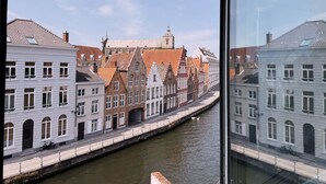 Um canal com edifícios em ambos os lados, uma ponte e uma torre ao fundo.