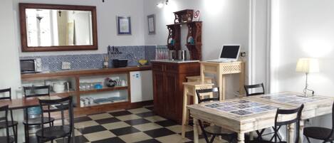 Uma cozinha com piso xadrez, armários de madeira, micro-ondas, pia e uma mesa de jantar com cadeiras.