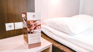 Um folheto sobre uma mesa de cabeceira em quarto de hotel, com uma cama bem arrumada e cabeceira de madeira.