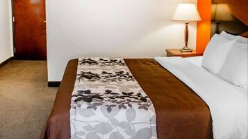 Quarto de hotel com cama, mesa de cabeceira e uma porta.
