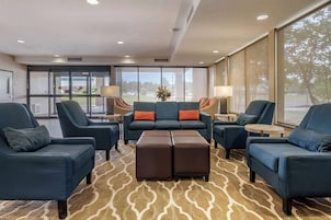 Um saguão de hotel com sofás, poltronas e uma mesa de centro.