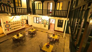 Uma área de refeições em vários níveis, com mesas, cadeiras e arte decorativa nas paredes.