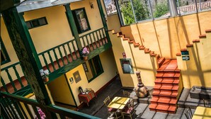 Um edifício amarelo com detalhes em verde, uma escadaria e área de estar externa.