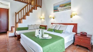 Quarto de hotel com escada de madeira, cama com roupa de cama verde, mesa de cabeceira e um quadro na parede.