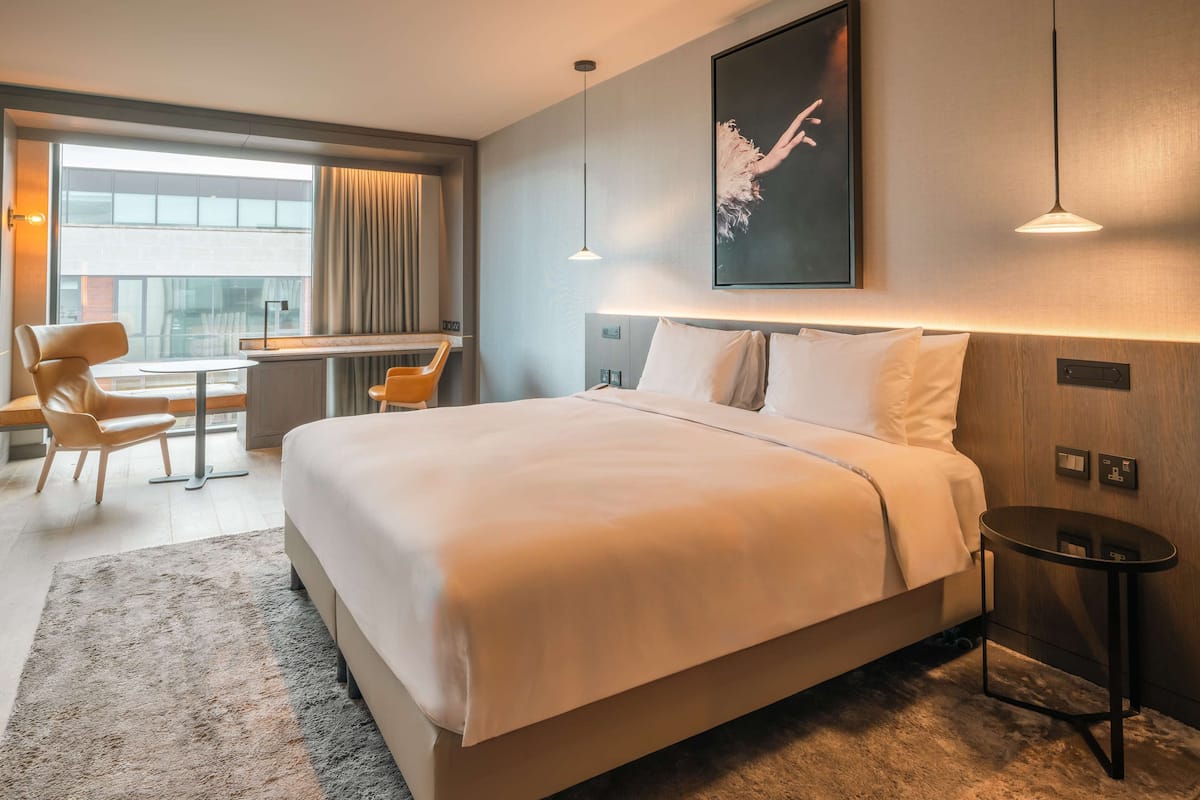Quarto de hotel moderno com uma cama grande, uma mesa e uma cadeira.