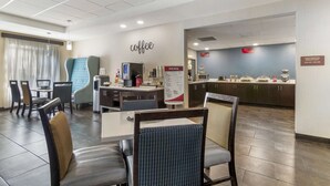 Um saguão de hotel com estação de café, área de estar e aviso sobre café da manhã continental.