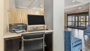 Uma mesa de recepção com computador, impressora e cadeira.