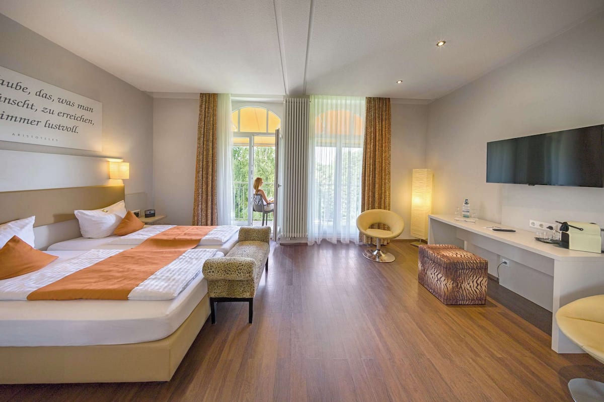 Quarto de hotel com uma cama grande, uma escrivaninha, uma cadeira e uma televisão.