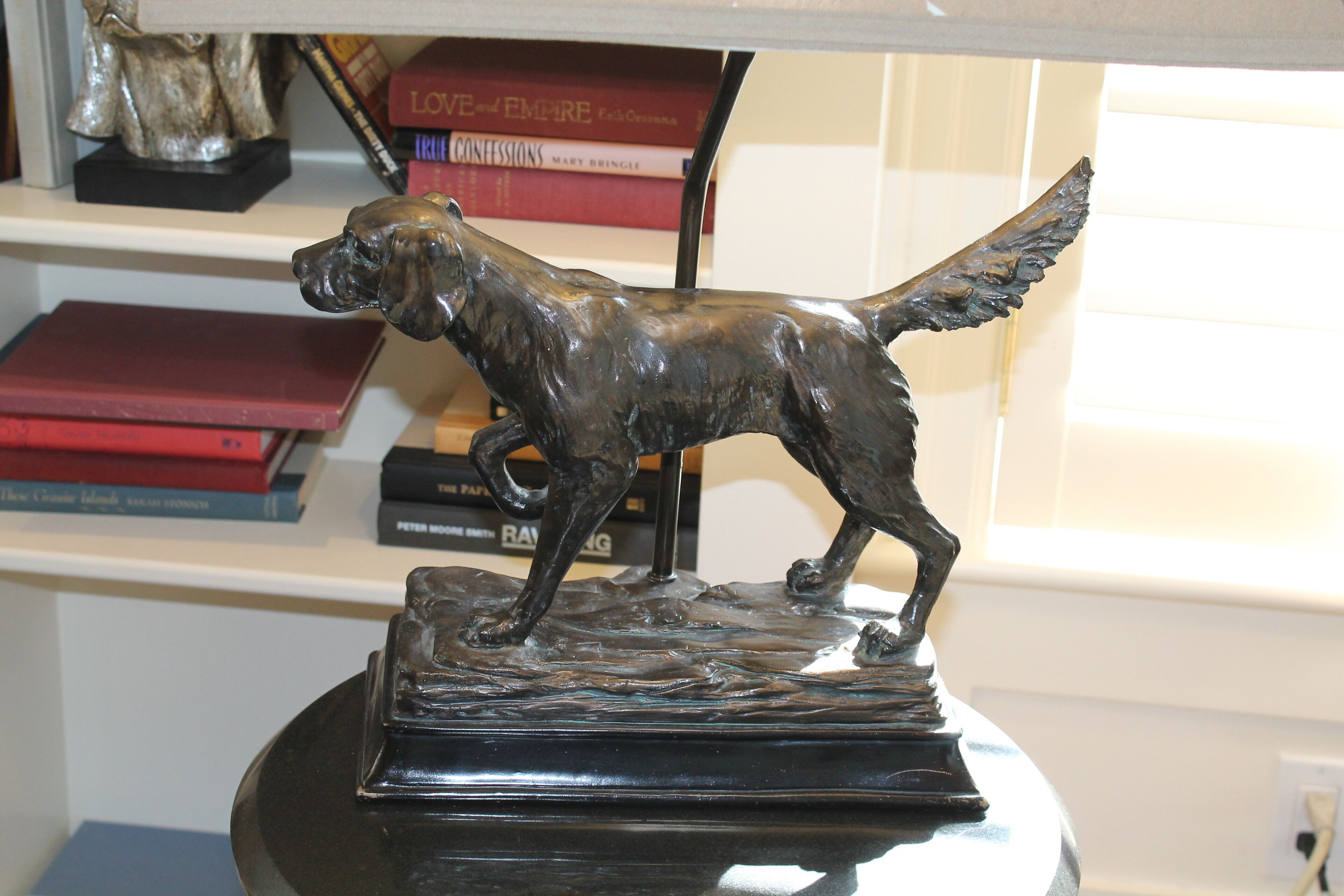 Estátua de bronze de um cão sobre um pedestal.