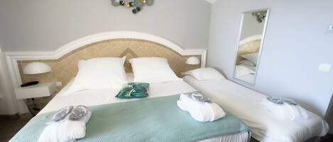 Quarto de hotel com uma cama grande, uma cama menor, um espelho e um ornamento na parede.
