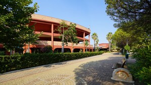 Um edifício com fachada vermelha, um caminho pavimentado e um banco.