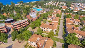 Vista aérea de uma área residencial com casas, piscina e um edifício grande com telhado curvo.